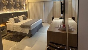 Quarto de hotel moderno com cama, mesa de cabeceira e um espelho grande.