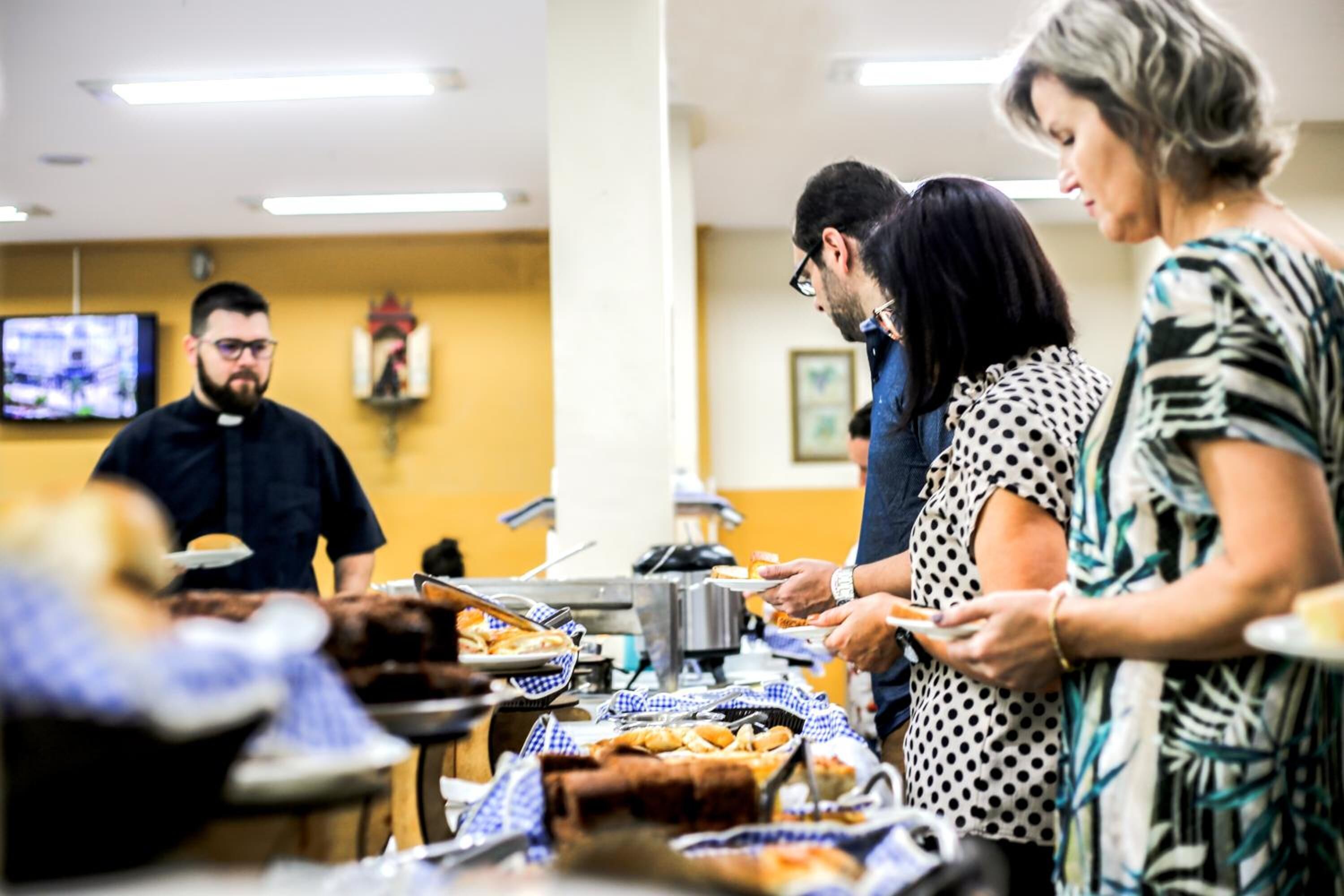 Buffet montado com diversos alimentos e uma pessoa servindo.