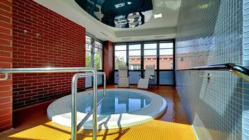 Uma piscina interior moderna com parede de vidro, parede de tijolos e chão ladrilhado.