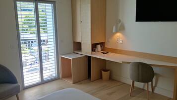 Quarto moderno com porta de vidro deslizante para uma varanda, uma escrivaninha de madeira, uma cadeira e uma cama.