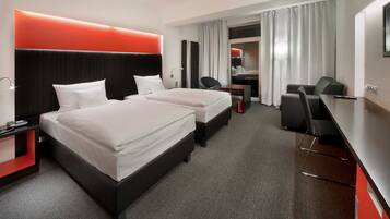 Quarto de hotel com duas camas, uma escrivaninha, uma cadeira e uma televisão.