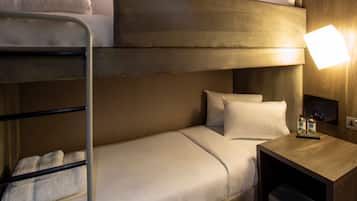 Quarto com beliche, escrivaninha, luminária e uma garrafa de água.