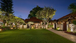 Um jardim bem cuidado com um caminho que leva a um edifício com telhado de palha.