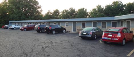 Um estacionamento com vários carros estacionados em frente a um motel com quartos numerados.