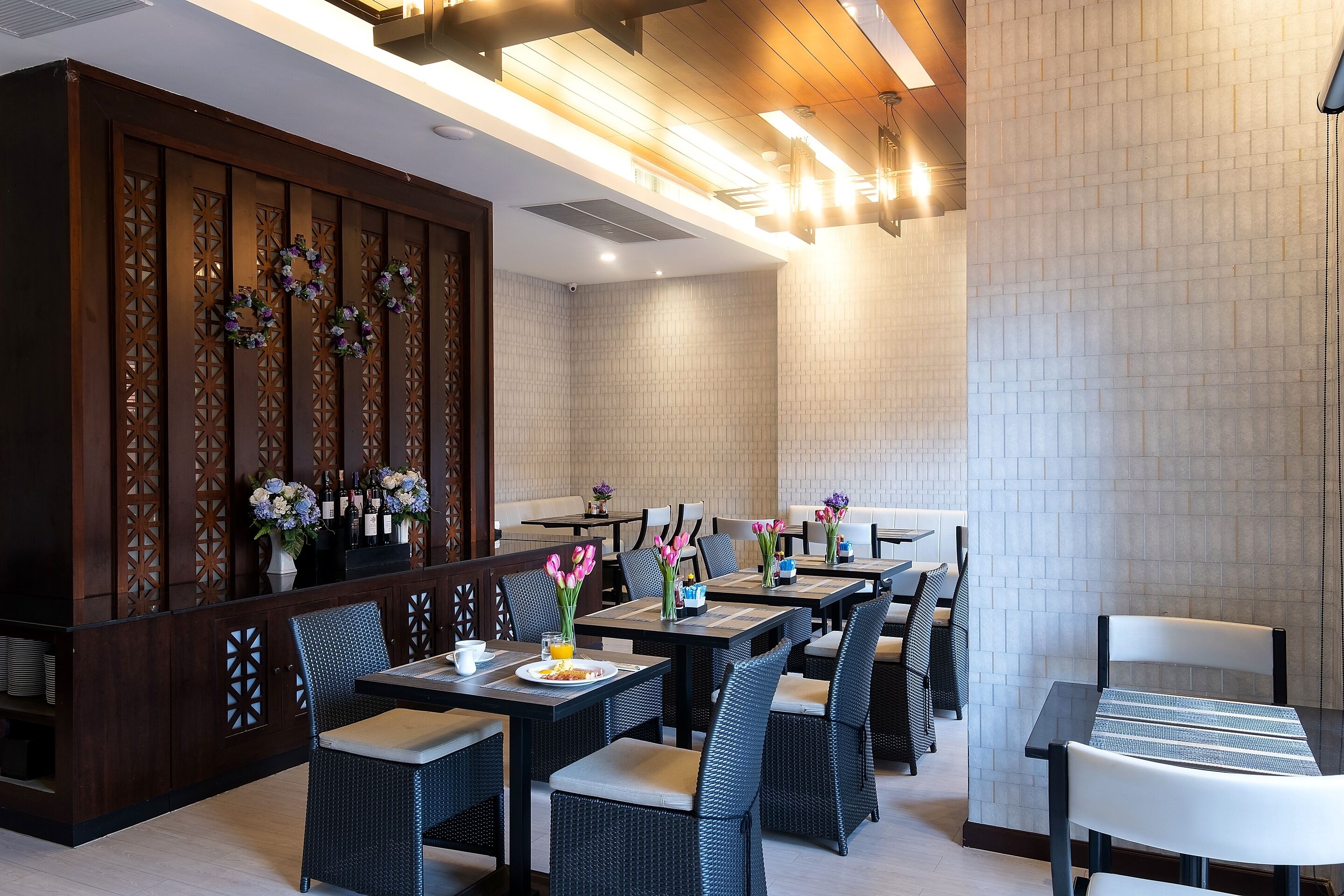 Um restaurante com parede de tijolos, painéis de madeira e móveis de vime.