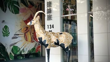 Uma estátua de girafa em frente a um prédio com um mural de uma mulher tocando violão.