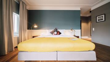 Quarto moderno com cama grande, luminária de cabeceira e vista para o corredor.