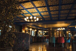 Uma área de bar com teto estampado, várias luminárias pendentes e diferentes opções de assentos.