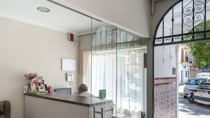 Uma área de recepção com divisória de vidro, balcão de atendimento e vista para a rua.