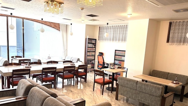 Um hall de hotel moderno com área de refeições, assentos e uma estante de livros.