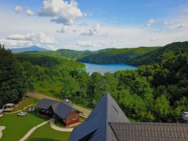 Uma pousada com um prédio vermelho e um grande lago azul rodeado por colinas arborizadas.