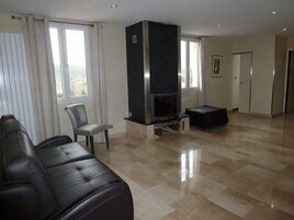 Uma sala de estar espaçosa com um sofá de couro preto, uma TV de tela plana e uma lareira.