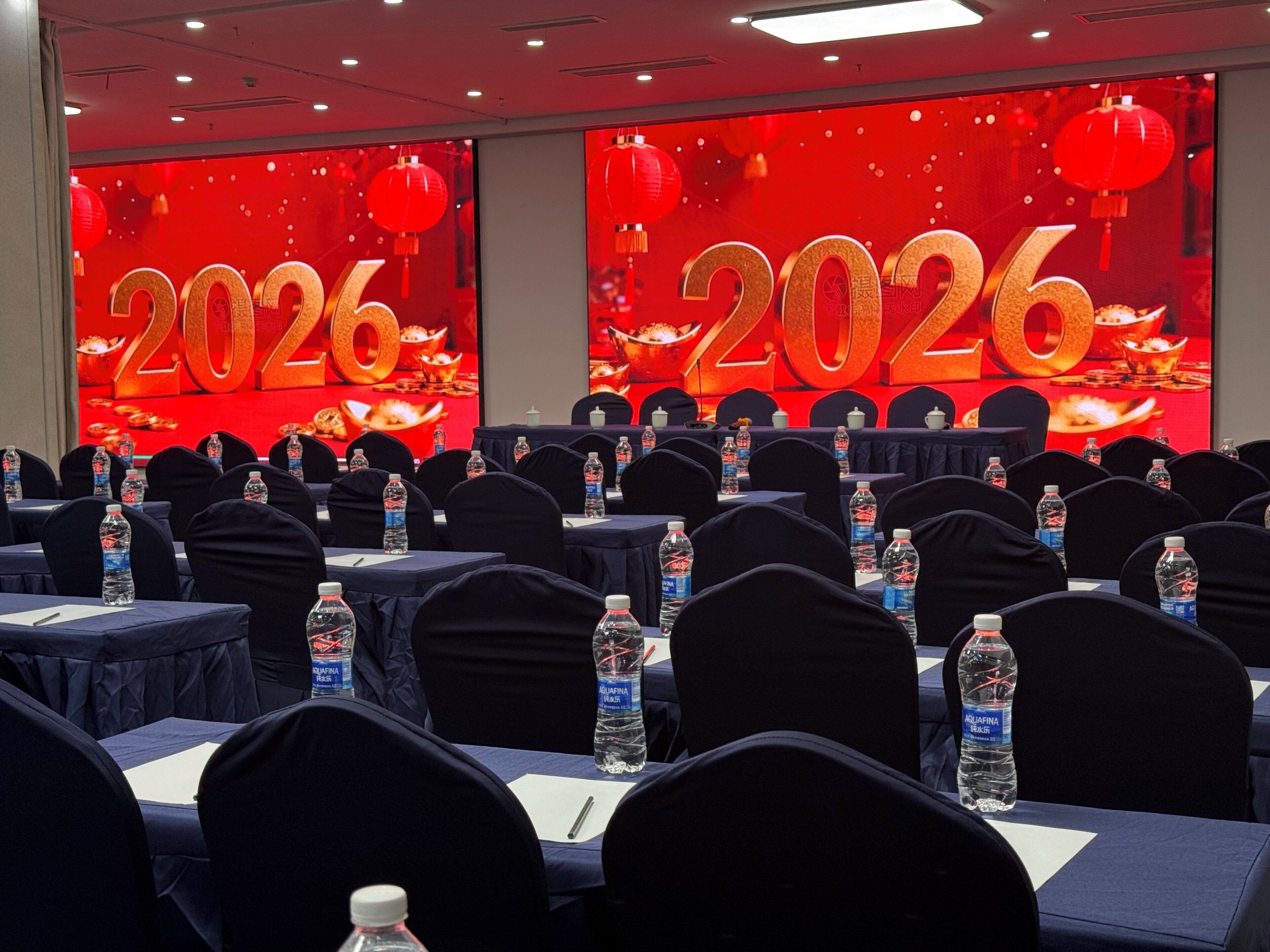 Uma sala de conferência com mesas preparadas para uma reunião, cada uma com uma garrafa de água e bloco de anotações.