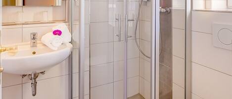 Uma casa de banho moderna com cabine de duche em vidro, lavatório branco e sanita.
