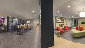 Um hall de hotel moderno com balcão de recepção, área de estar e um café.