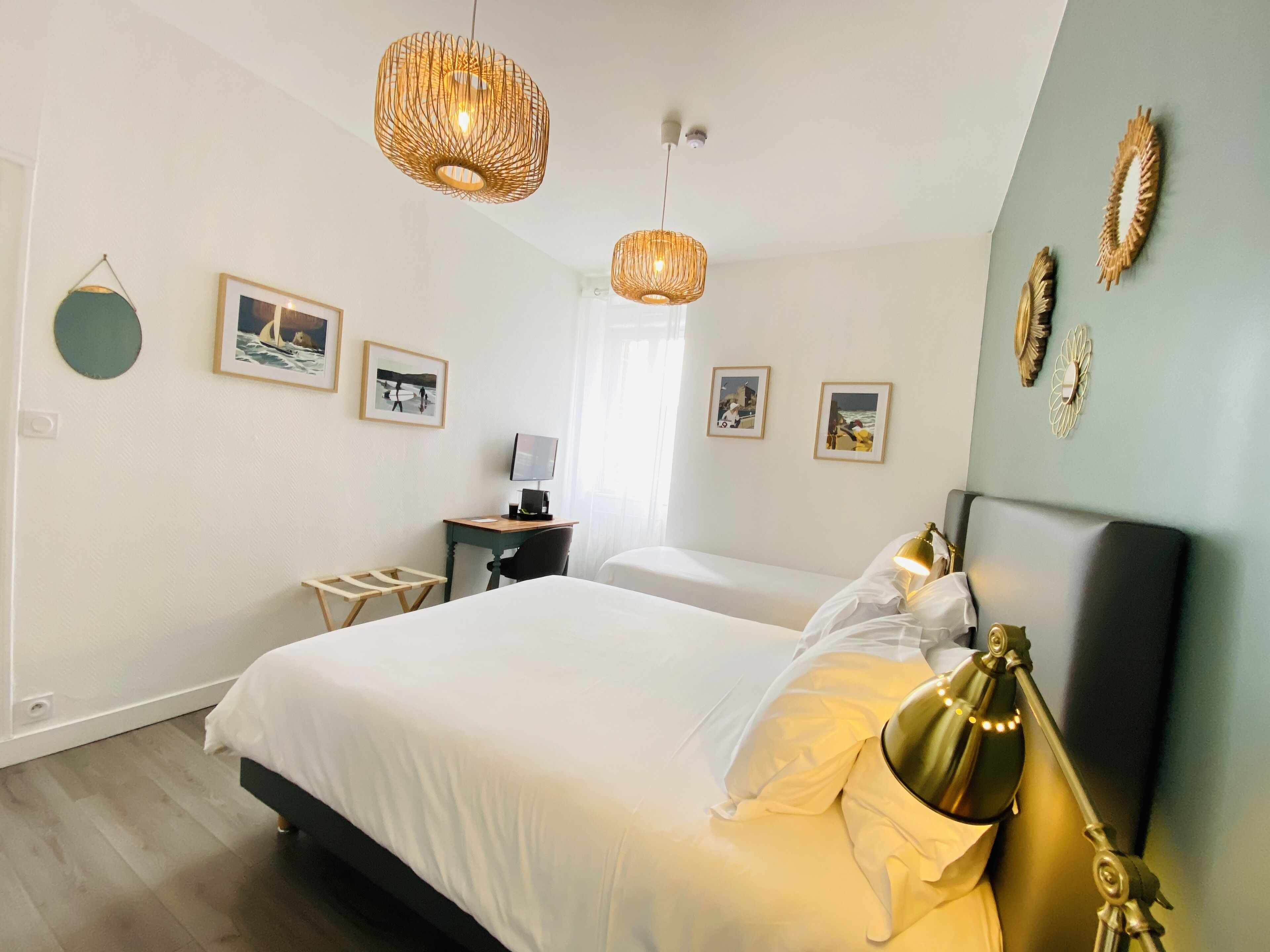 Quarto de hotel moderno com uma cama grande, uma escrivaninha e duas luminárias fixadas na parede.