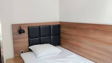 Uma cama bem arrumada com cabeceira de madeira e uma pequena mesa de cabeceira.