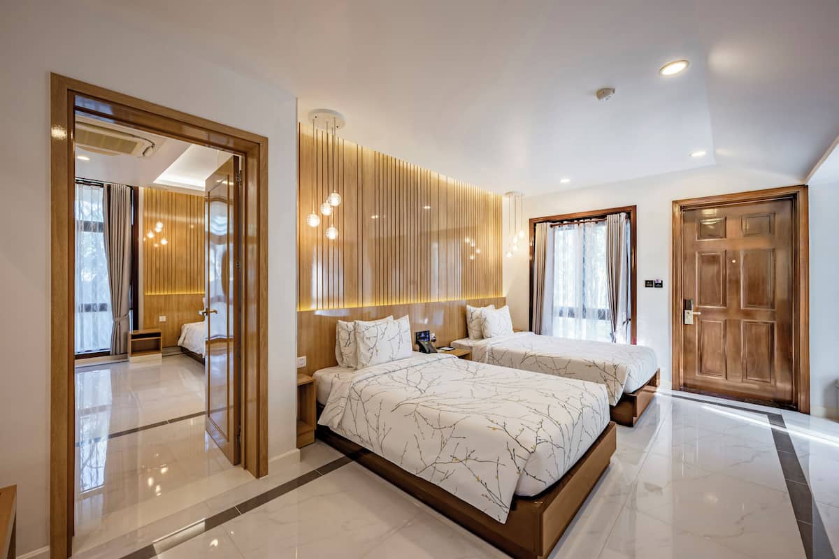 Quarto de hotel moderno com uma cama grande, mesas de cabeceira, um espelho e painel de parede de madeira.