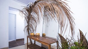 Uma mesa de madeira com cestos e um banco em um quarto com chão ladrilhado e uma porta branca.