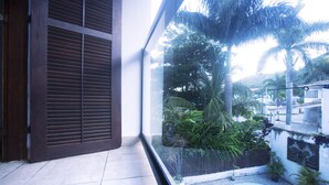 Uma varanda com vista para uma piscina, rodeada por vegetação exuberante e palmeiras.