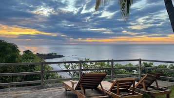 Um deck de madeira com espreguiçadeiras com vista para a costa.