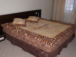 Uma cama com colcha estampada em padrão de zebra e travesseiro decorativo com um nome.