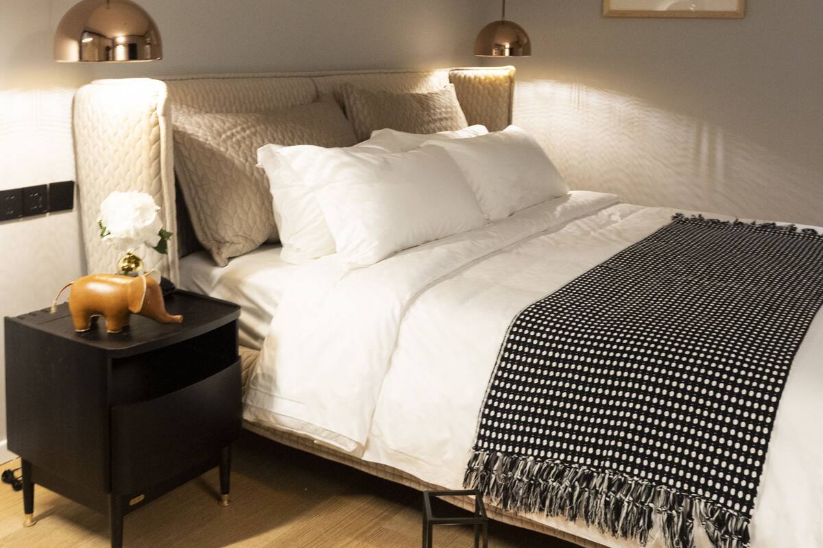 Um quarto bem arrumado, com uma cama, mesas de cabeceira e um quadro na parede.