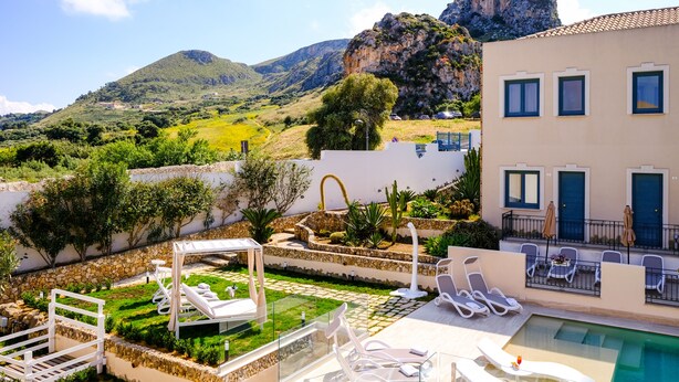 Área da piscina com espreguiçadeiras, um pequeno jardim e vista para uma paisagem montanhosa.