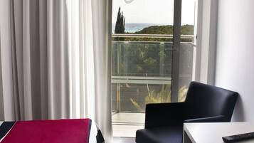 Quarto de hotel com varanda, cama, escrivaninha e cadeira.