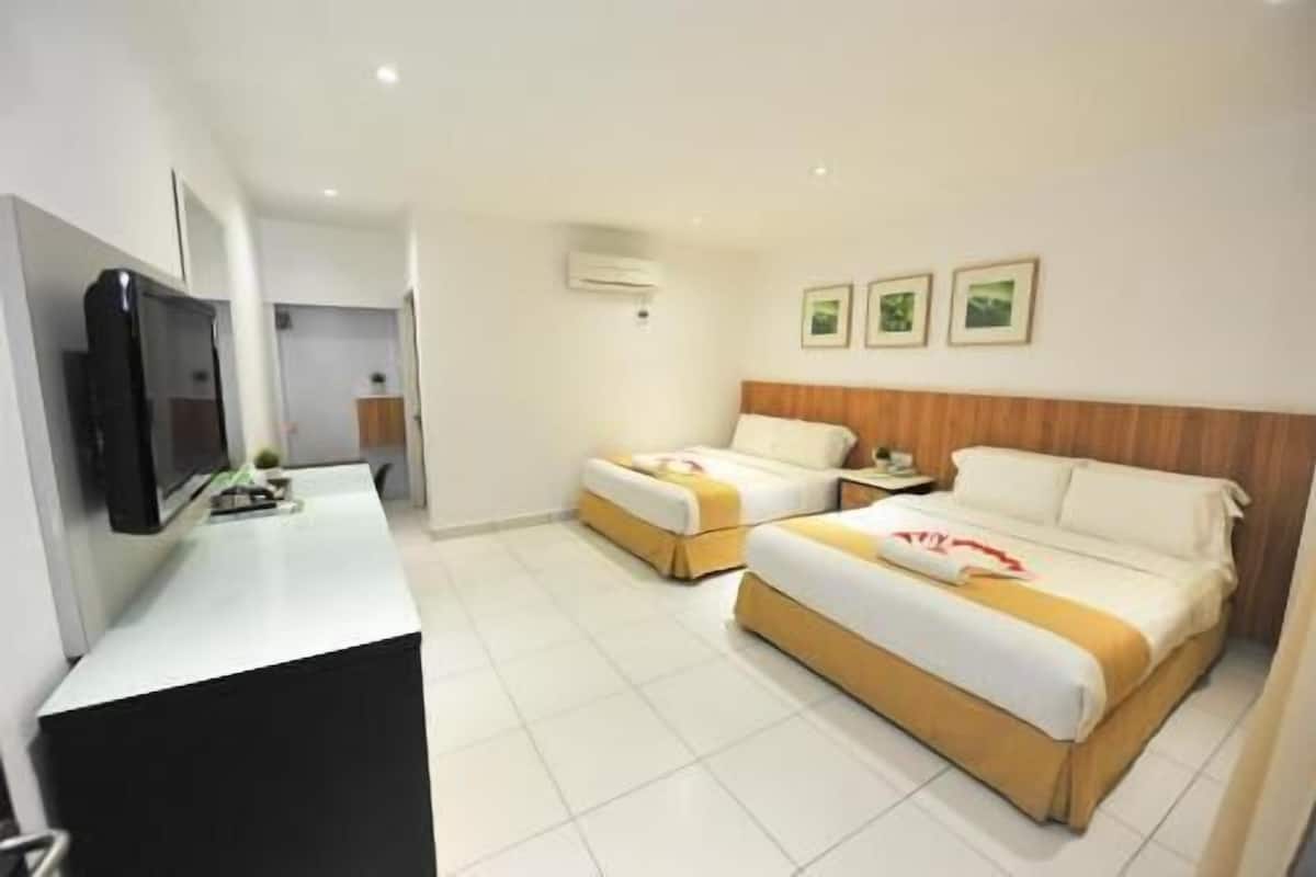 Quarto de hotel com duas camas, uma televisão e uma escrivaninha.