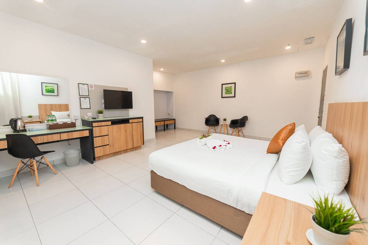 Quarto de hotel moderno com uma cama grande, uma escrivaninha e um espaço de estar.