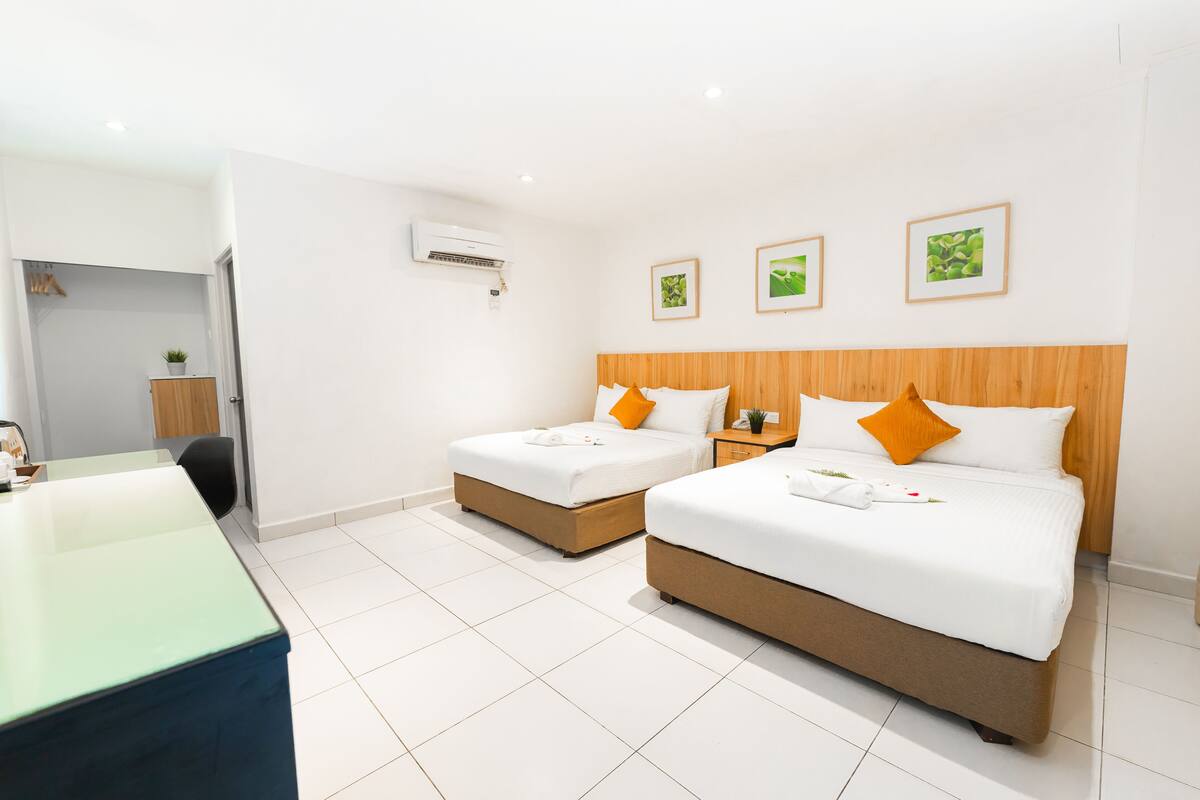 Quarto de hotel com duas camas, uma escrivaninha e uma cadeira.