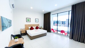 Quarto de hotel moderno com uma cama grande, uma escrivaninha e vista da cidade através de amplas janelas.