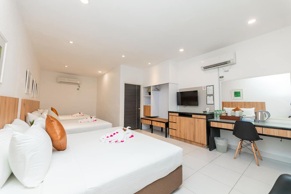 Quarto de hotel com duas camas, uma escrivaninha, uma cadeira, uma TV e uma cozinha compacta.