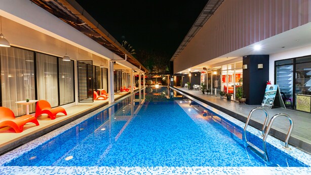 Uma área de piscina de hotel com piscina transparente, espreguiçadeiras e um bar.