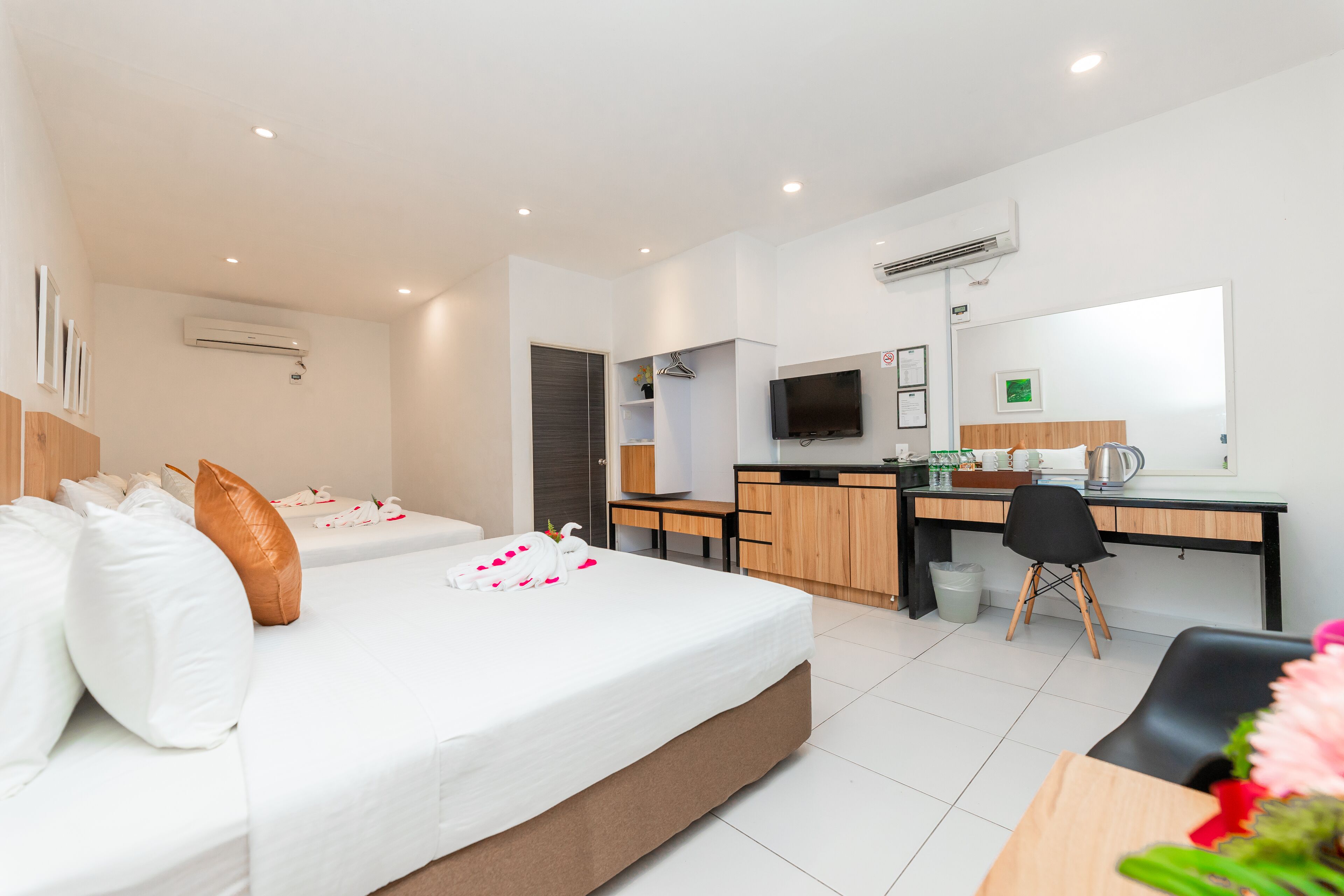 Quarto de hotel com cama, escrivaninha, cadeira, televisão e ar condicionado.