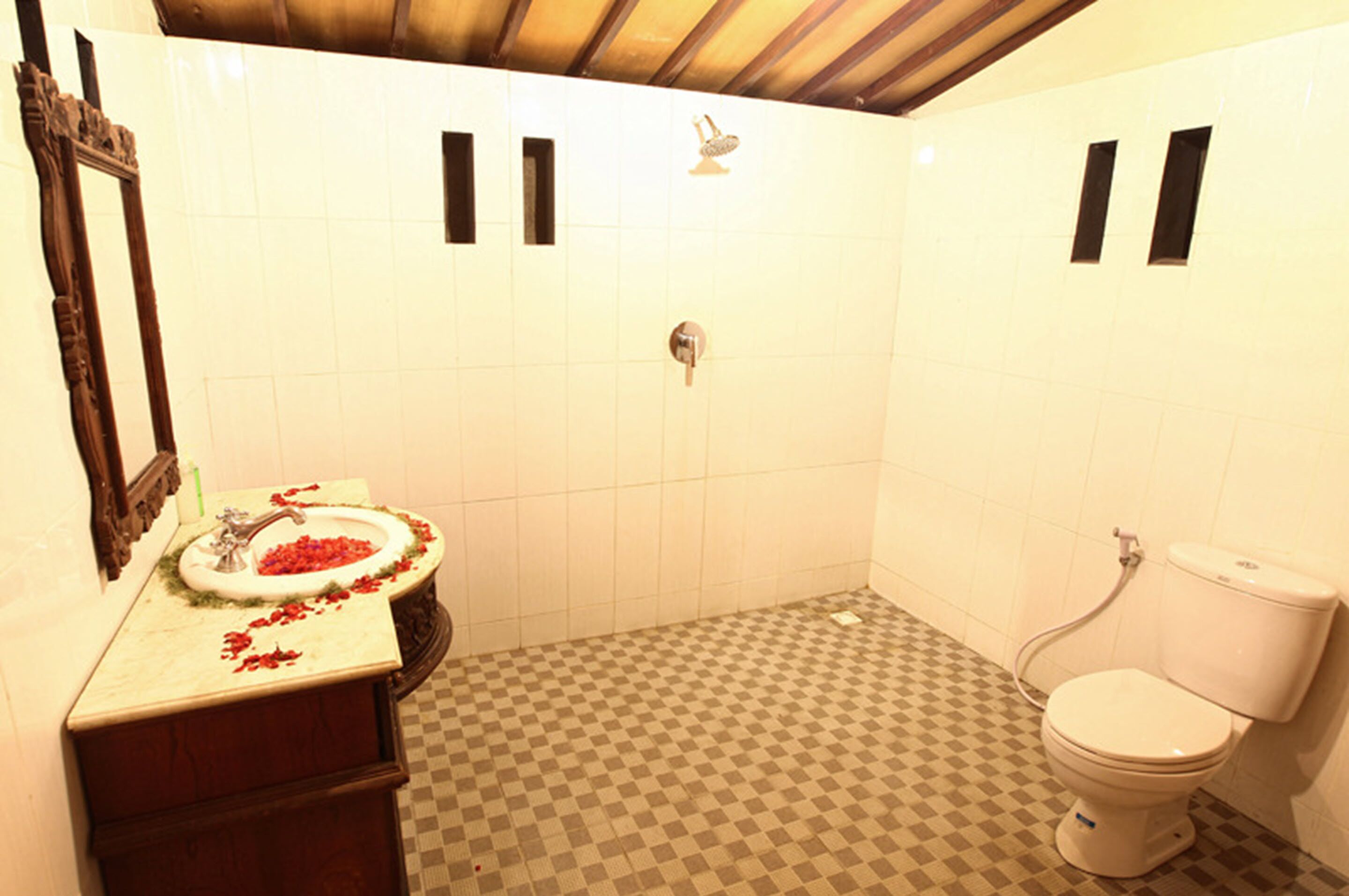 Casa de banho com chão quadriculado, sanita e lavatório com espelho decorativo.