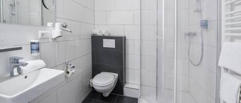 Um banheiro moderno com pia, vaso sanitário e chuveiro com divisória de vidro.