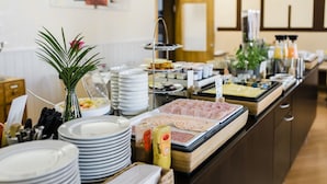 Disposição de buffet com diversos alimentos, pratos e acompanhamentos.