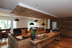 Um interior moderno com detalhes em madeira, uma área de estar central e iluminação pendente.