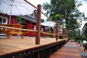 Um deck de madeira com barreiras de corda, mesas de piquenique e guarda-sóis.