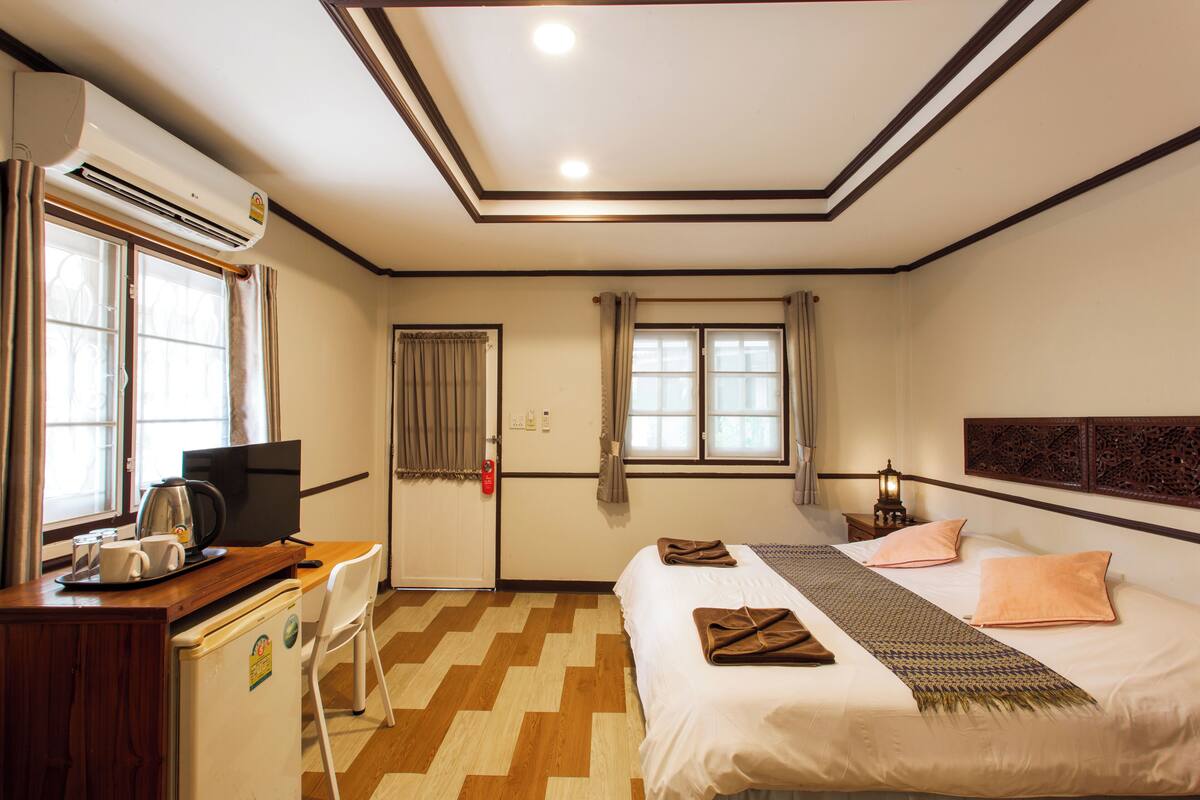 Quarto de hotel com cama, escrivaninha e ar condicionado.
