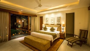 Quarto de hotel moderno com uma cama grande, um espaço de estar e varanda com velas.
