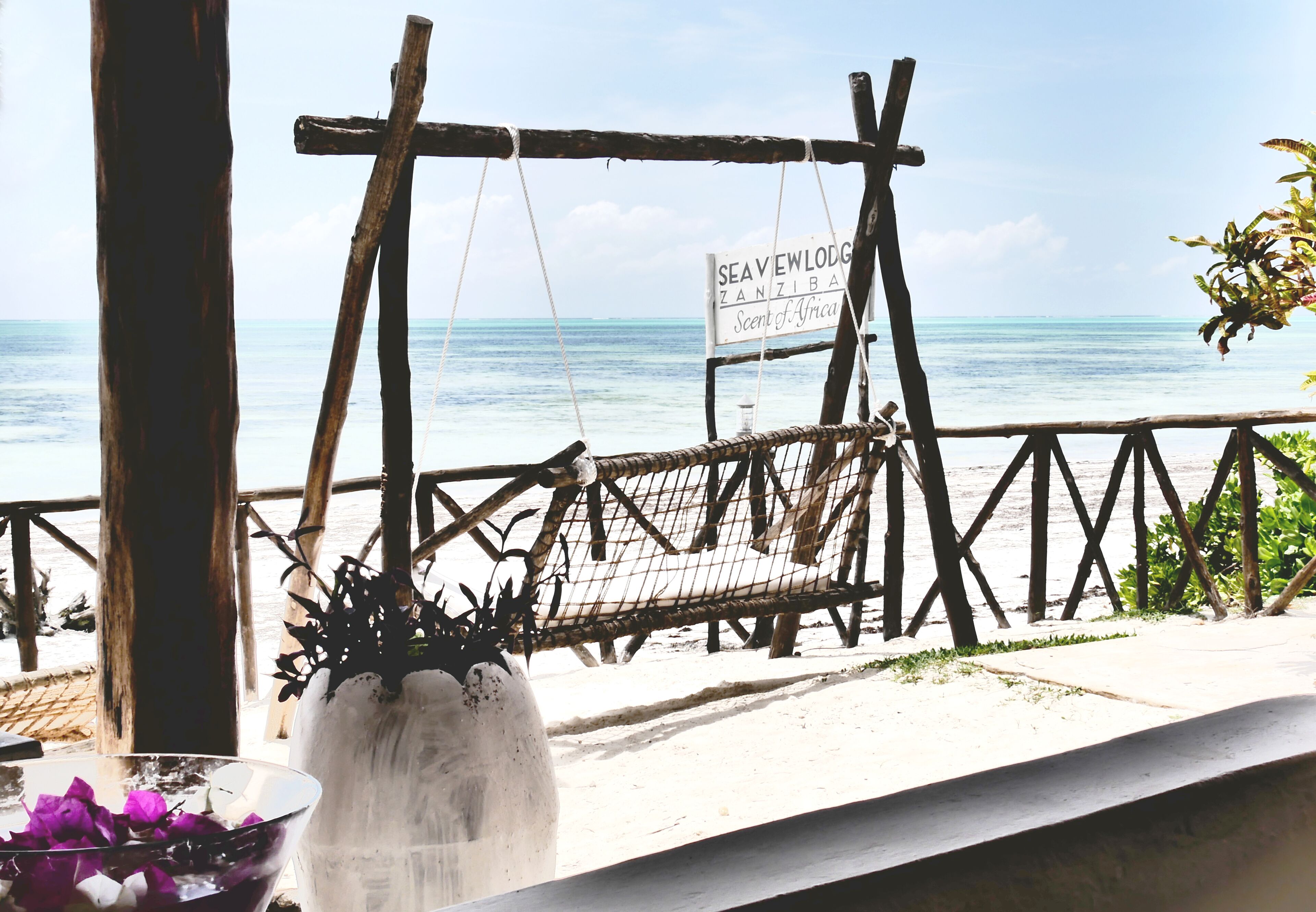 Vista da praia com baloiço de madeira e placa a indicar Seaview Lodge Zanzibar.