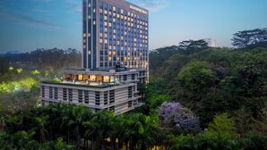 Um hotel com vários andares e design moderno, rodeado por vegetação exuberante.