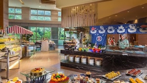 Uma área de buffet com diversos alimentos e um chef preparando refeições.
