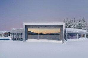 Um edifício moderno com grandes janelas de vidro e paisagem coberta de neve.