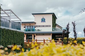 Um hotel moderno com terraço no telhado, um logotipo no edifício e uma placa com o nome do hotel.