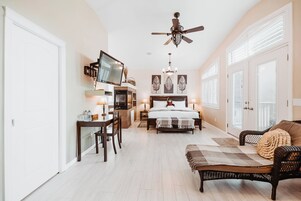 Um quarto espaçoso com uma cama grande, uma escrivaninha e uma televisão.