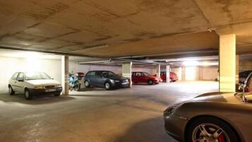 Garagem de estacionamento em vários níveis, com pilares de concreto e alguns carros estacionados.